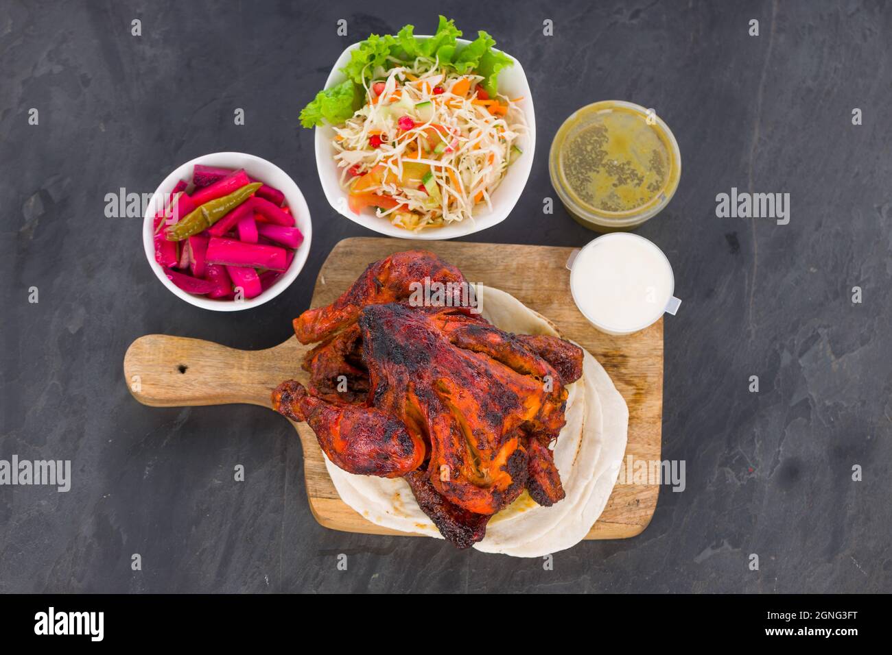 Shawai chicken arranged on a wooden base with kuboos and side dishes on ...