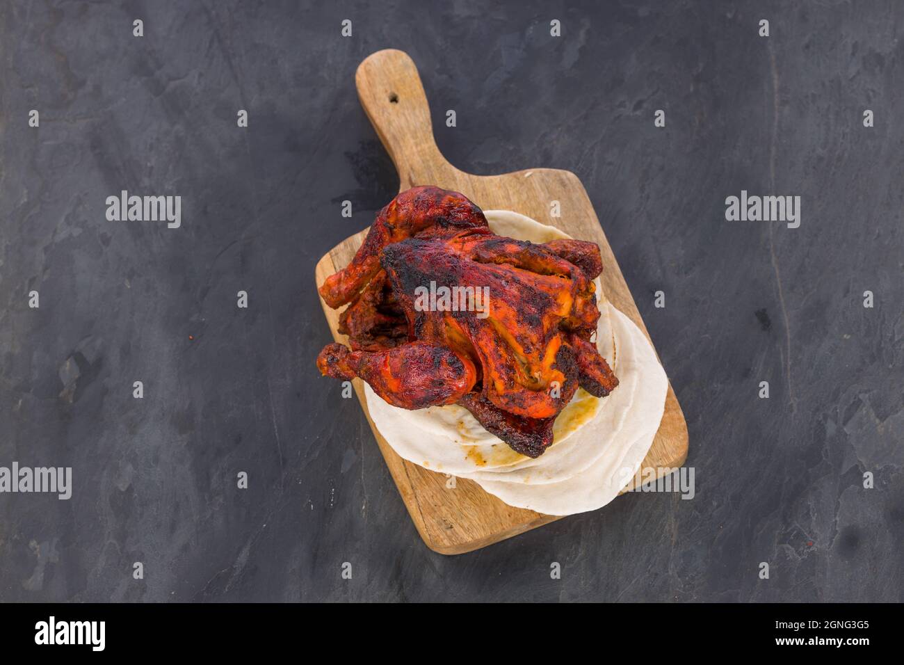 Shawai chicken arranged on a wooden base with kuboos on grey textured ...