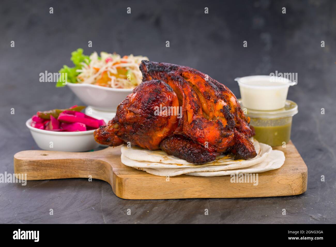 Shawai chicken arranged on a wooden base with kuboos and side dishes on ...