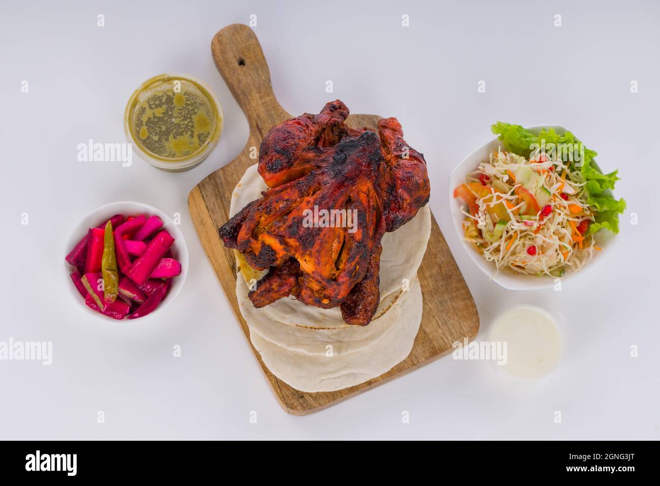 Shawai chicken arranged on a wooden base with kuboos and side dishes on ...