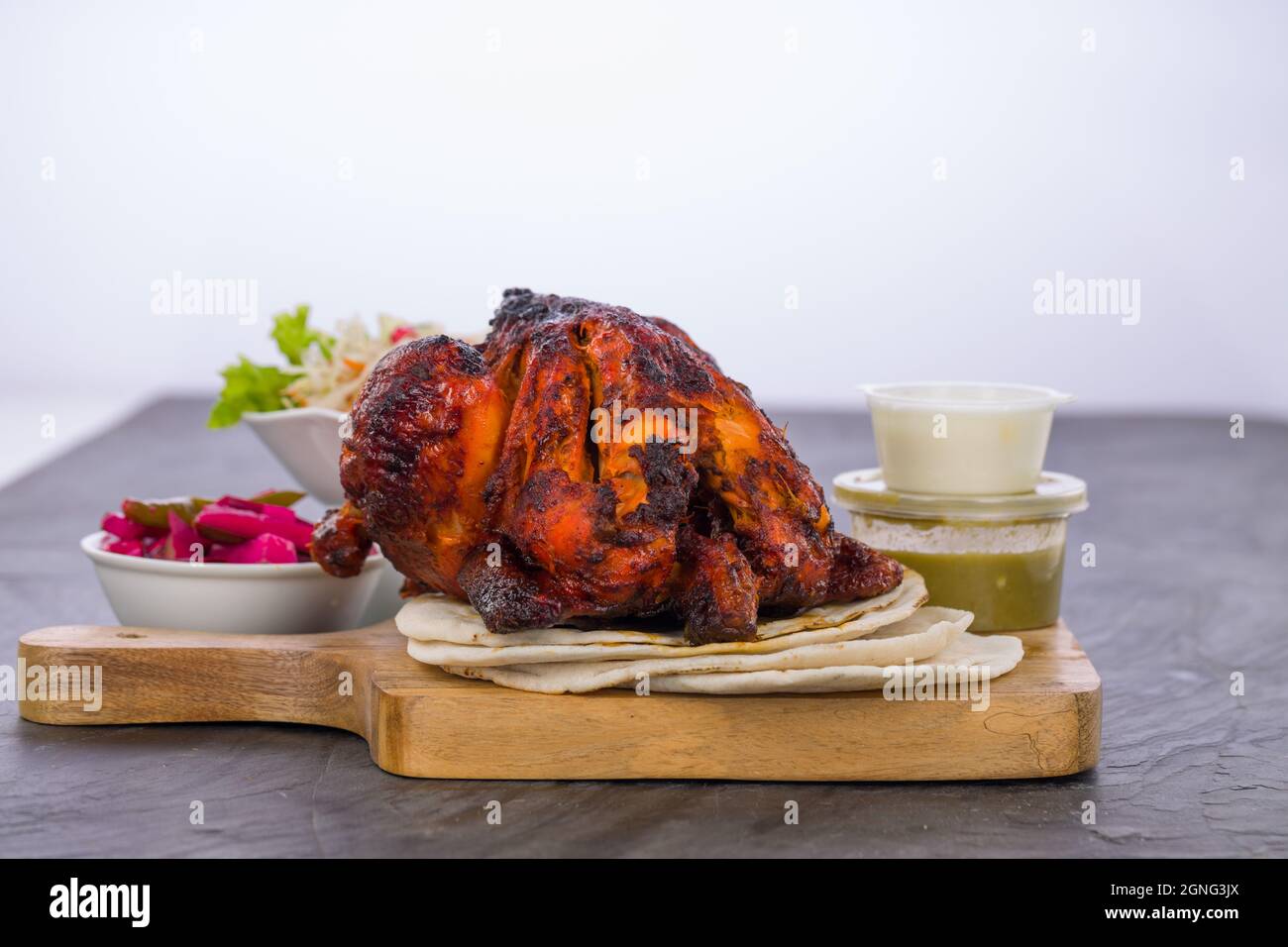Shawai chicken arranged on a wooden base with kuboos and side dishes on ...