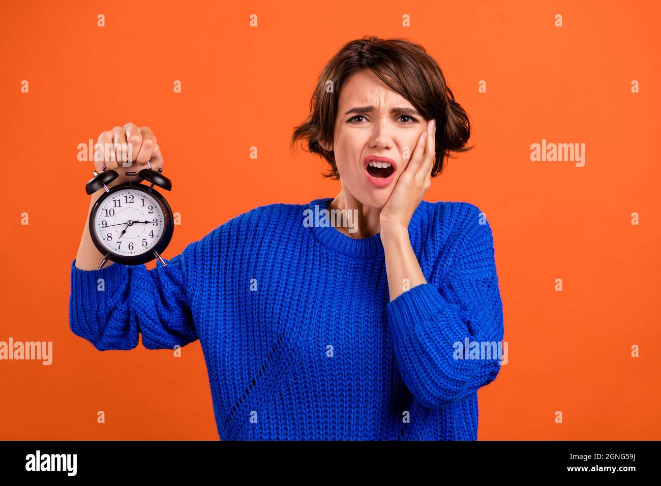 Portrait of attractive worried girl holding in hands clock bad mood ...