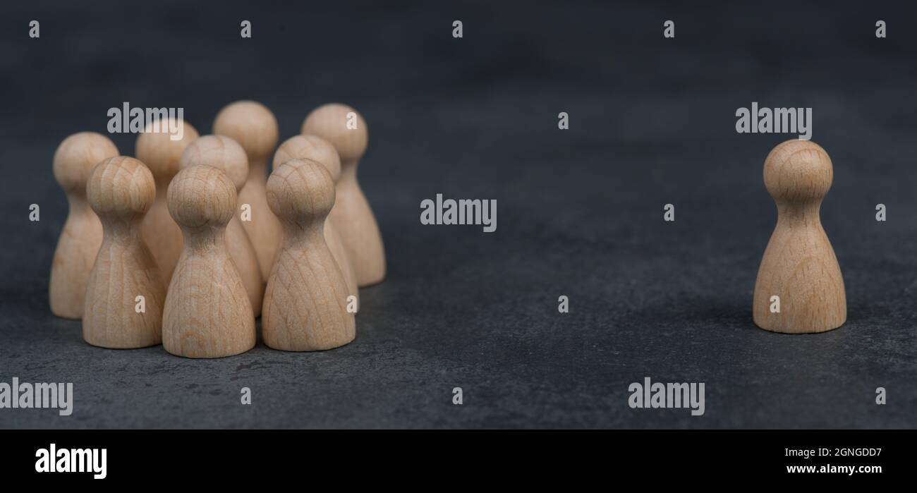 Group of wooden figures standing together, one leader standing alone on ...