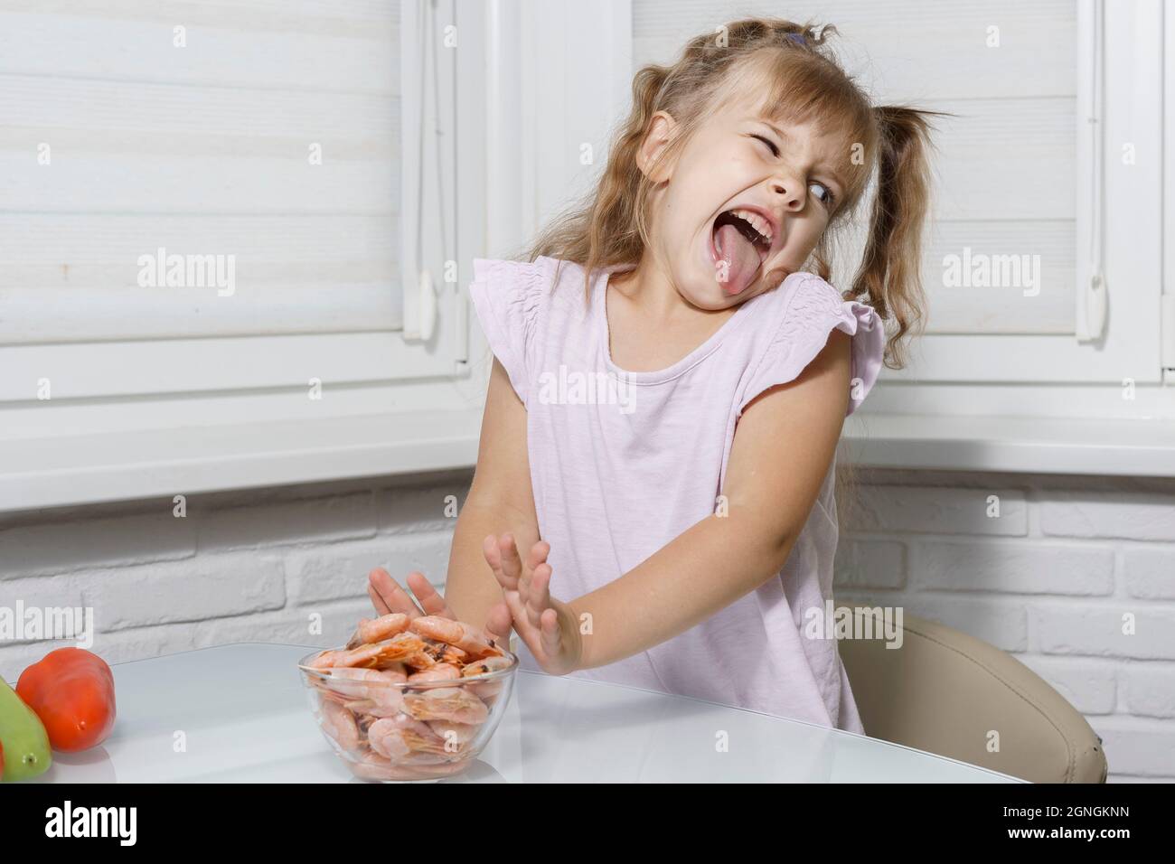 Caucasian child girl refuses to eat shrimp. A kid not hungry, hate fish ...