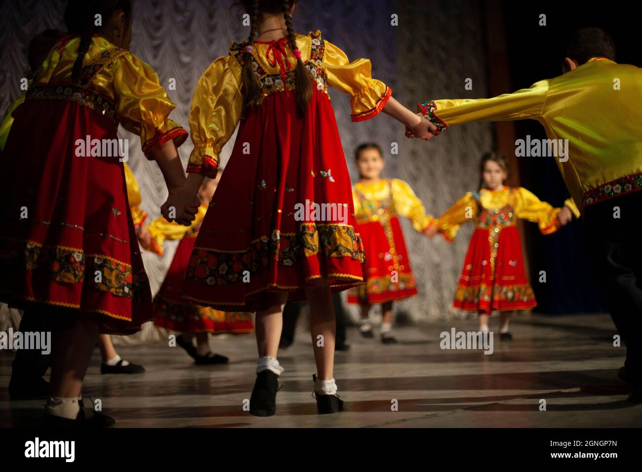 Children in folk costumes lead a round dance. Performance on stage ...