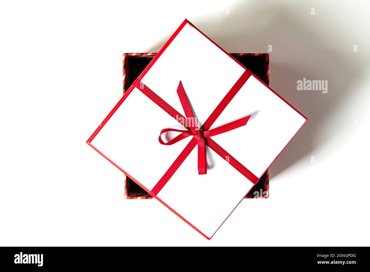Gift white box with red ribbon and bow isolated on white. View from ...
