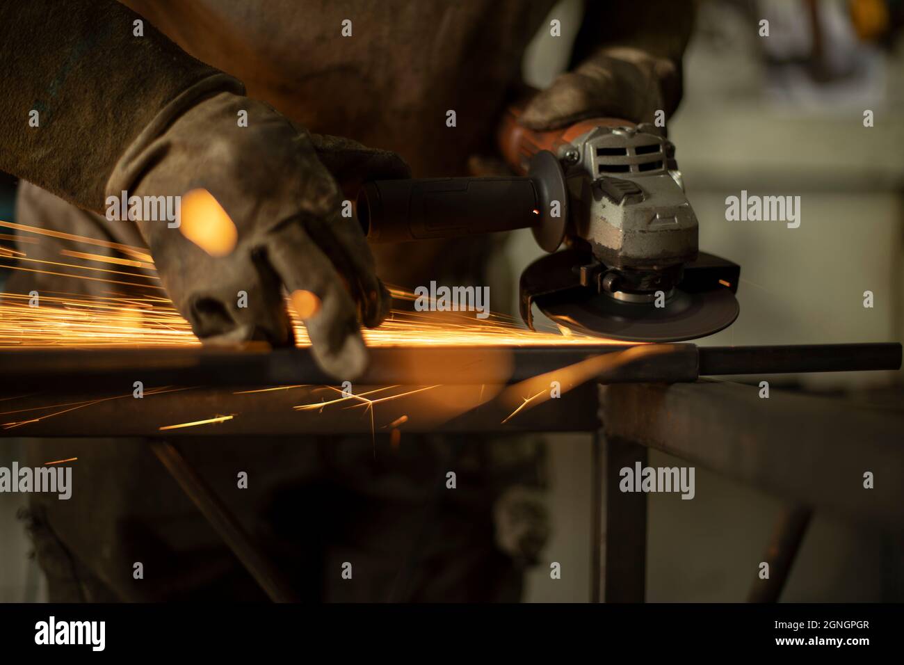 Metal processing with a grinder. Sparks from the tool. A man in the ...