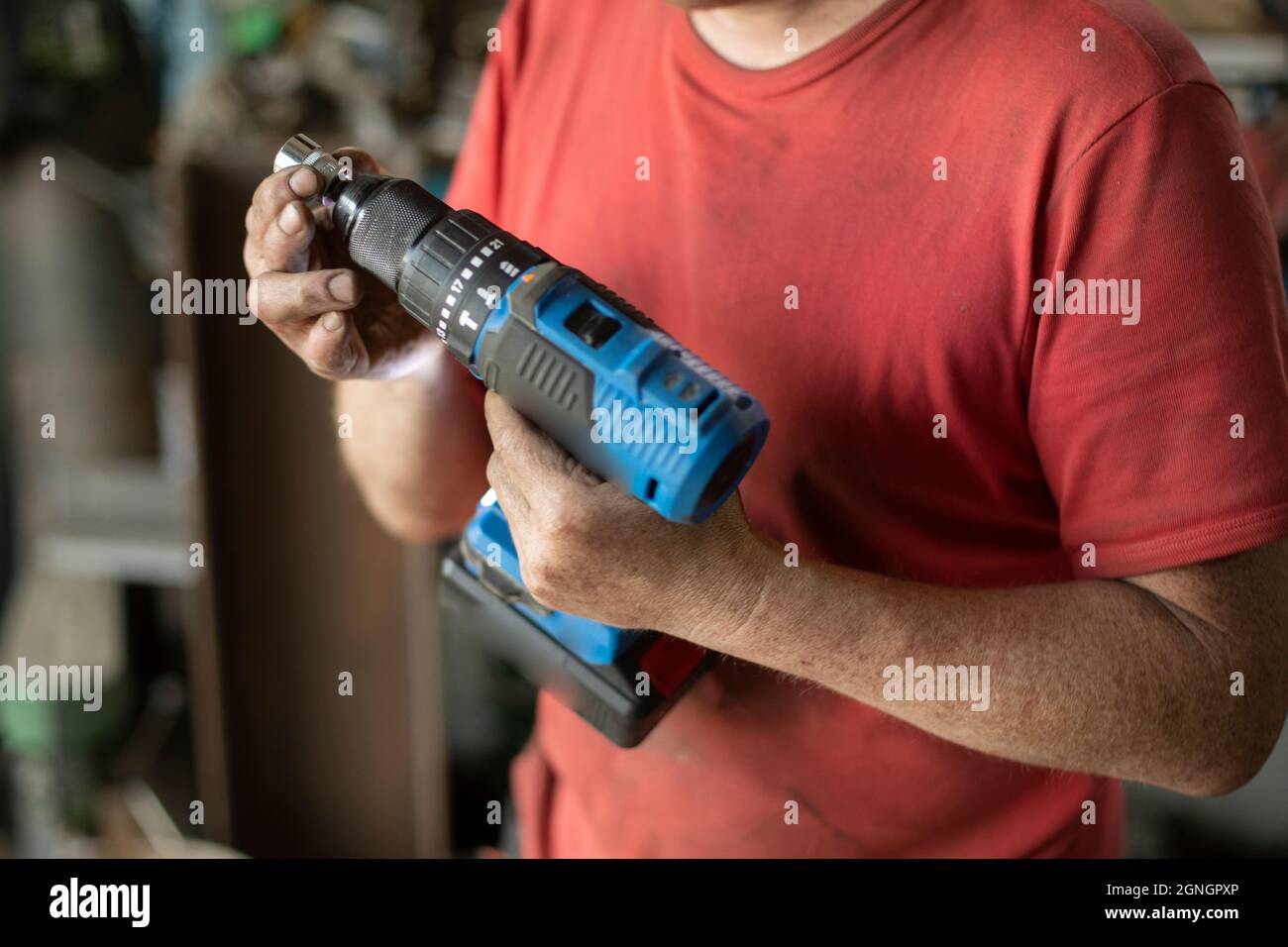 The man shows a screwdriver. A guy in a workshop with a power tool in ...