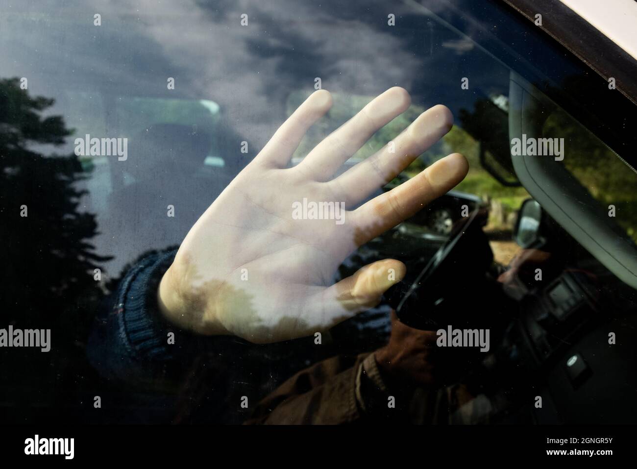 A hand of a child or young woman locked in the car with the reflections ...