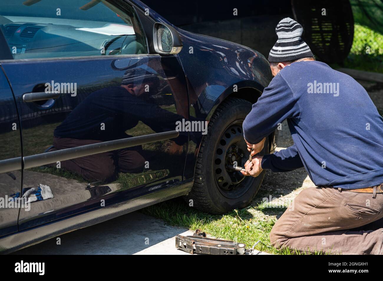 Mechanic changing wheel on car with manual wrench. Mechanic replacing ...