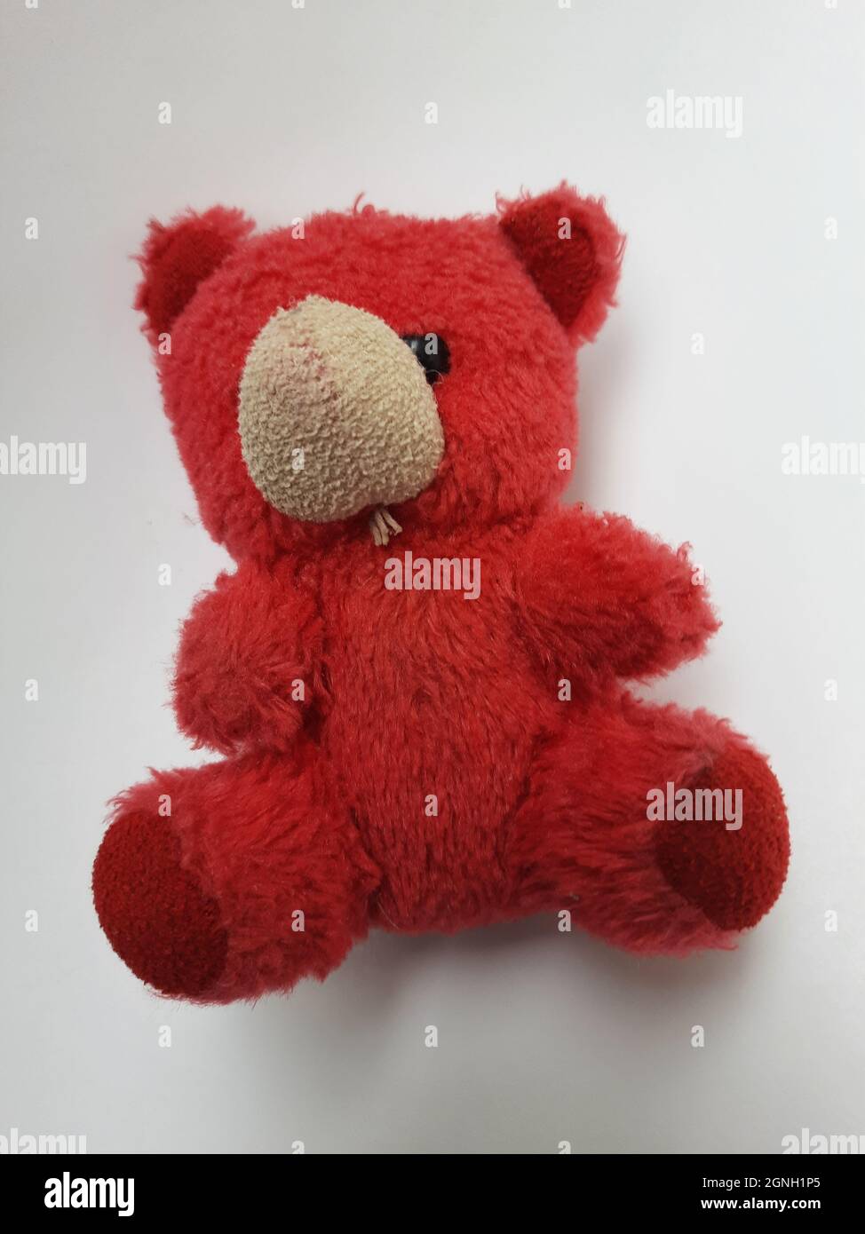 Top view of a small, red soft toy bear isolated on a white background ...