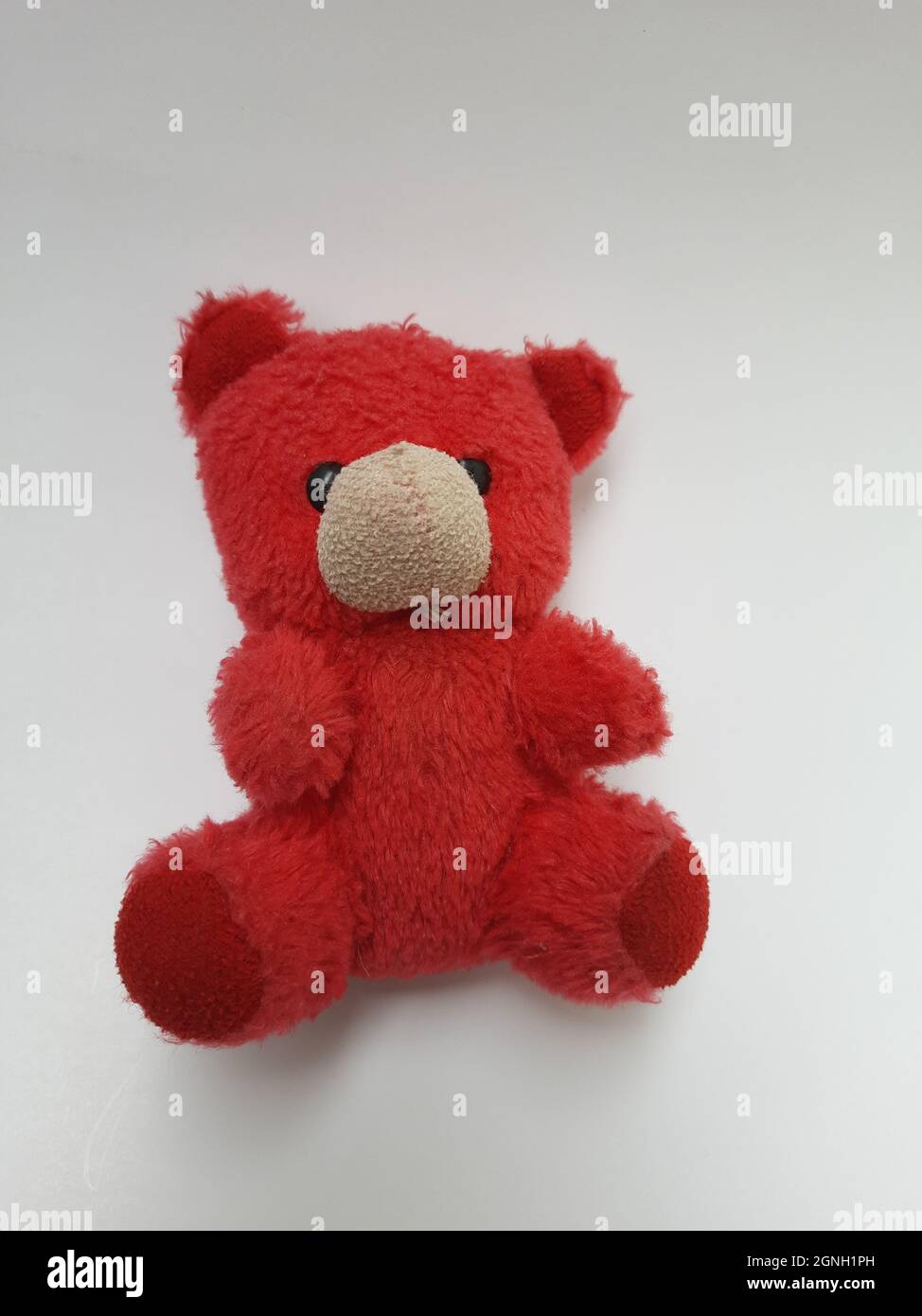 Top view of a small, red soft toy bear isolated on a white background ...