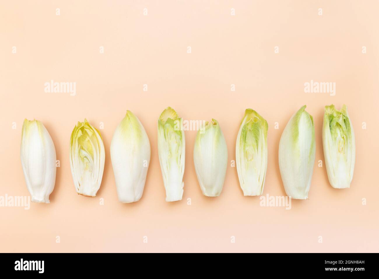 many raw endives salad roots or chicory on orange background, flat lay ...