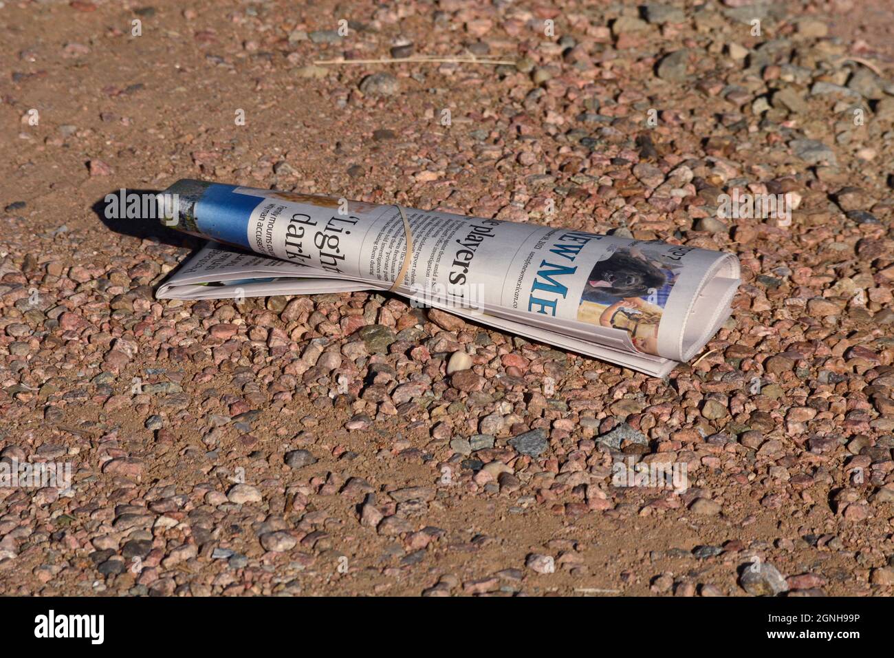 A home-delivered local daily newspaper in the driveway of a home in ...