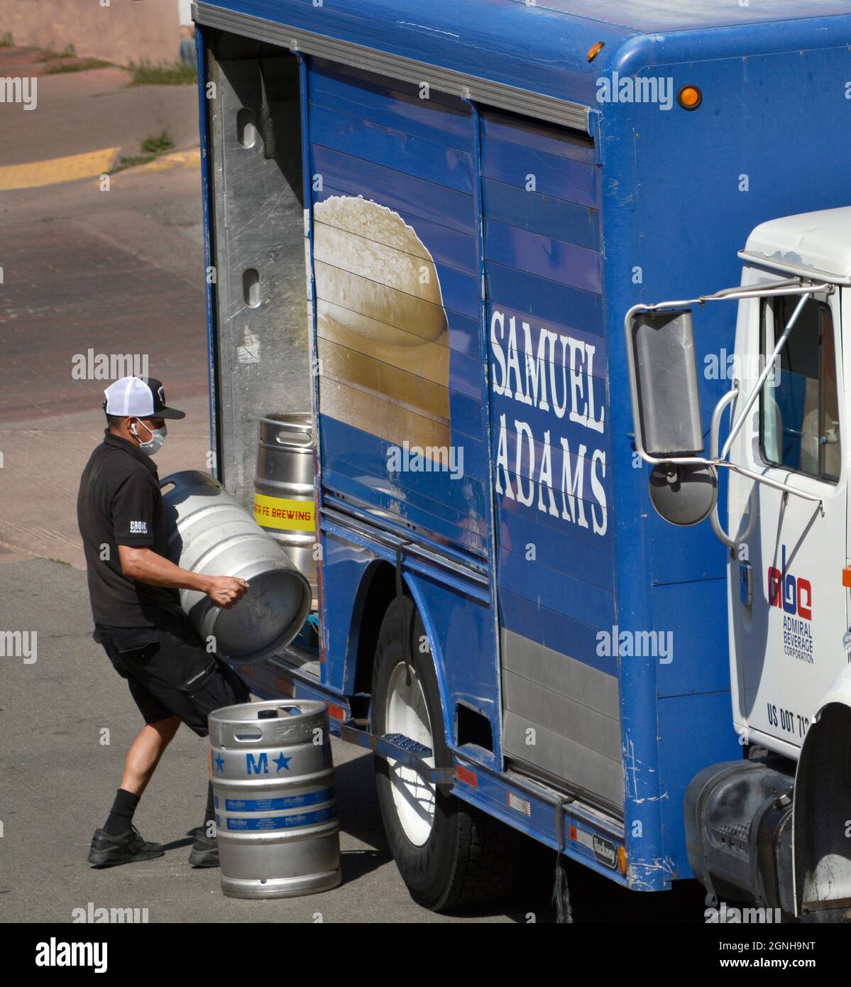 A beer deliveryman unloads kegs of beer to be delivered to a restaurant ...