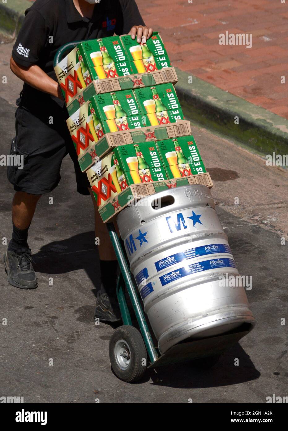 A beer deliveryman with a hand truck delivers cartons of Dos Equis ...