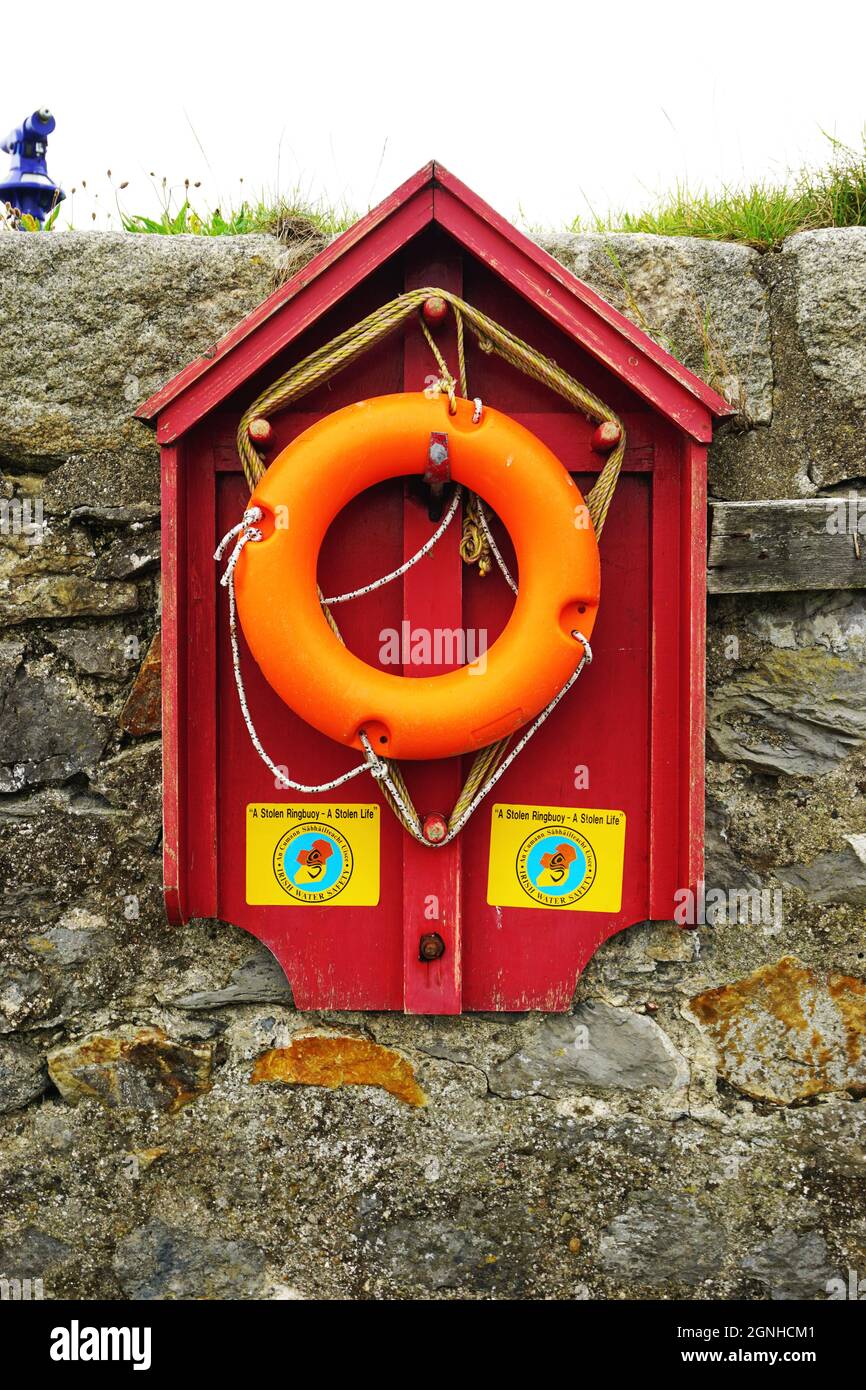 A bright orange lifesaving ring hangs on a red waterfront rescue ...