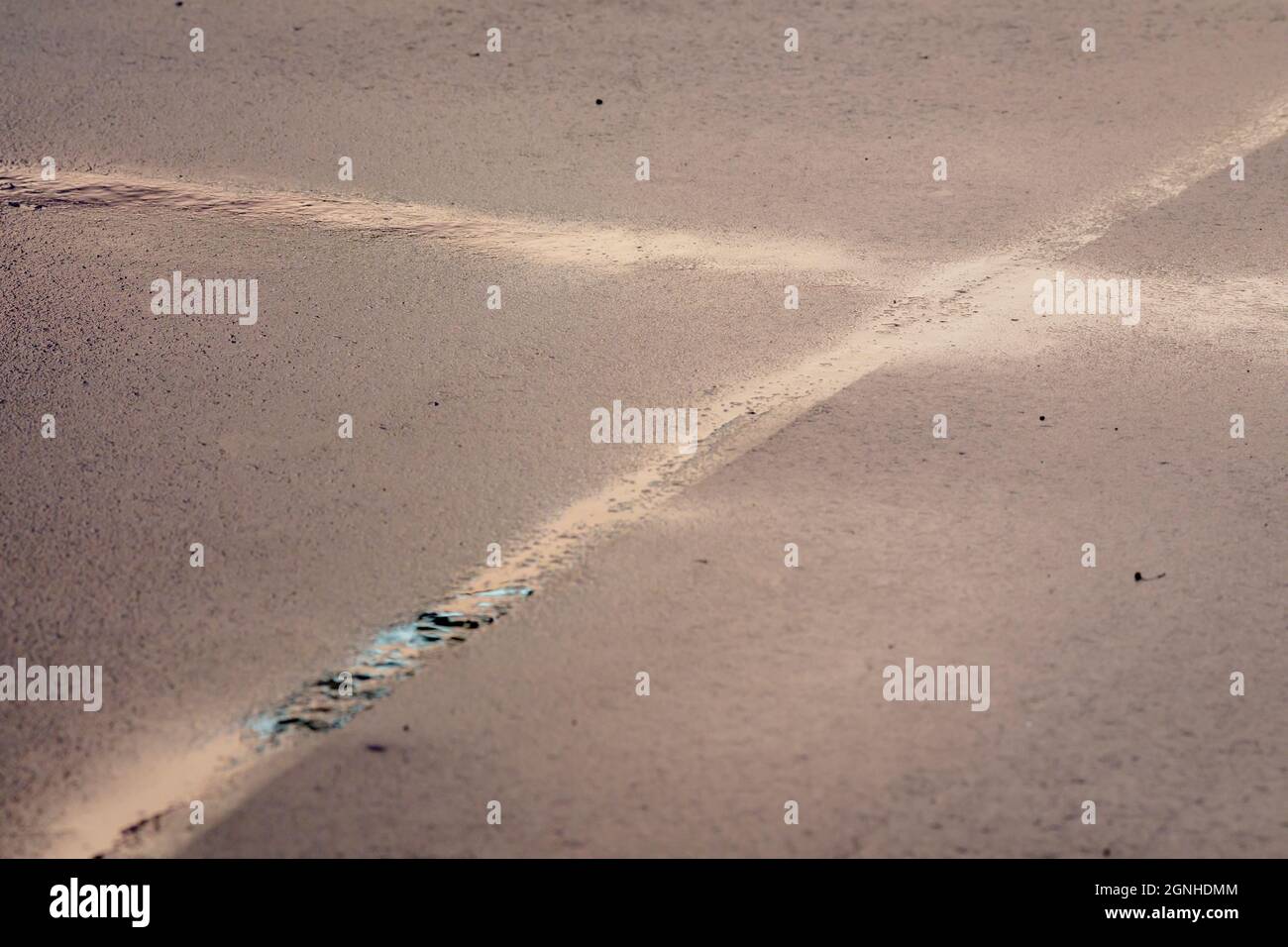 A groove in the asphalt forming a crosshair. Remains of water on the ...
