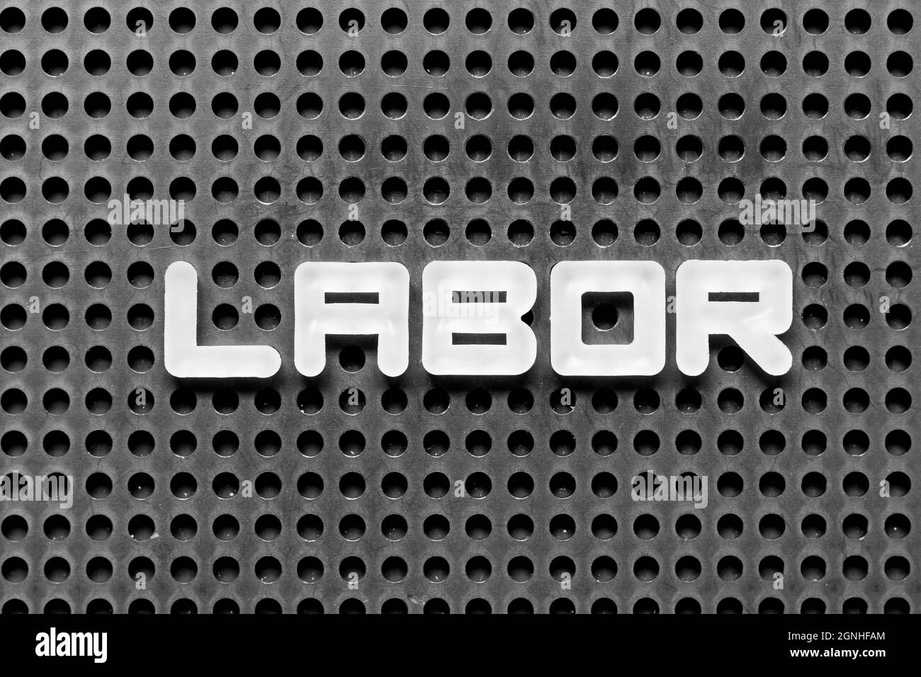 White alphabet letter in word labor on black pegboard background Stock ...