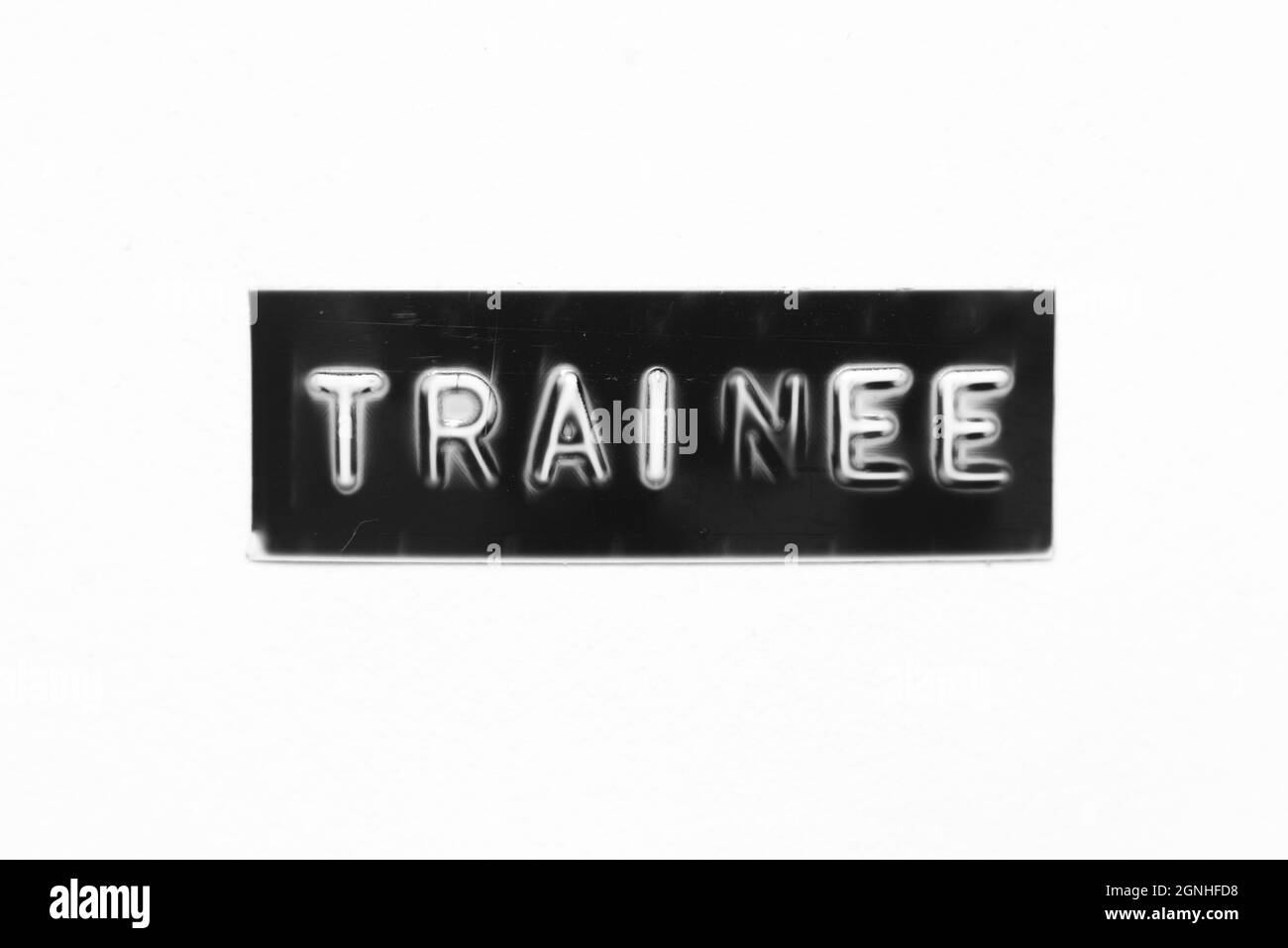 Black color banner that have embossed letter with word trainee on white ...