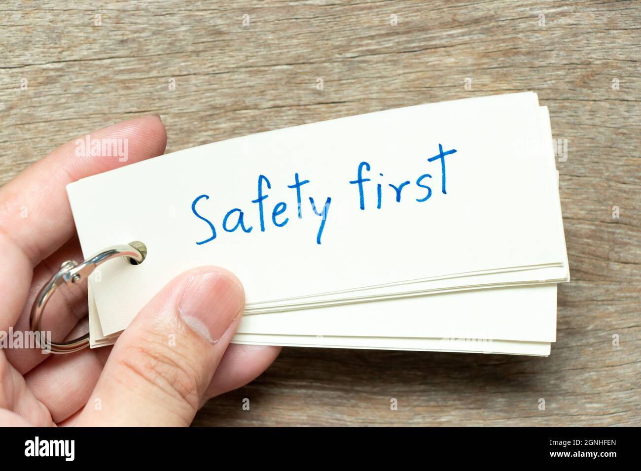 Man hold the flash card with handwriting word safety first on wood ...
