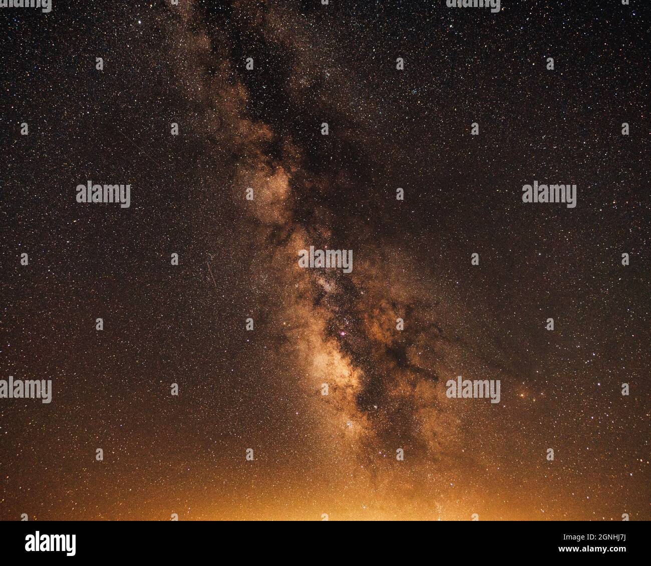 Orange sky with milky way galaxy and light pollution from a distant ...