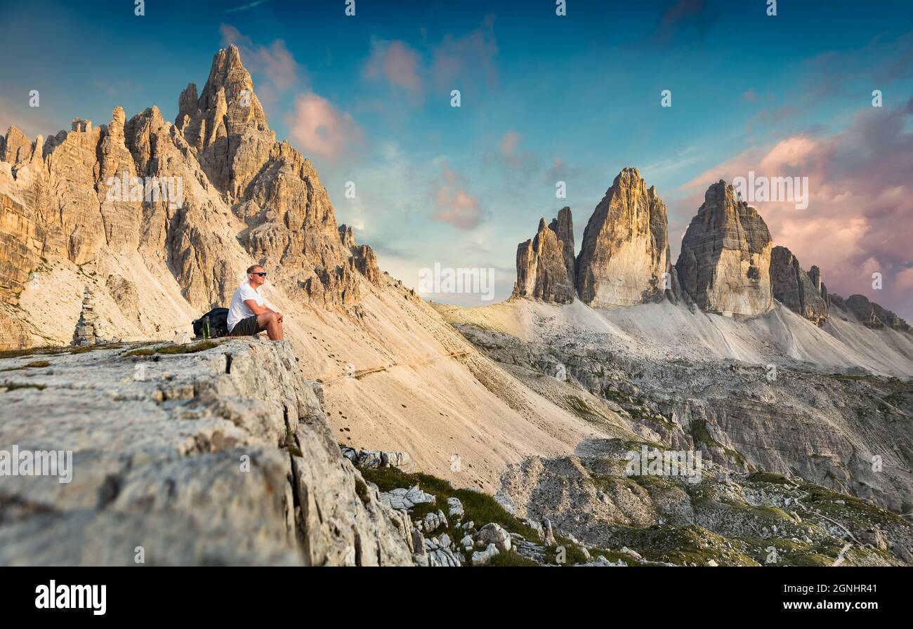 Tourist admires of Dolomiti Alps. Picturesque summer sunset with Tre Cime Di Lavaredo mountain ...