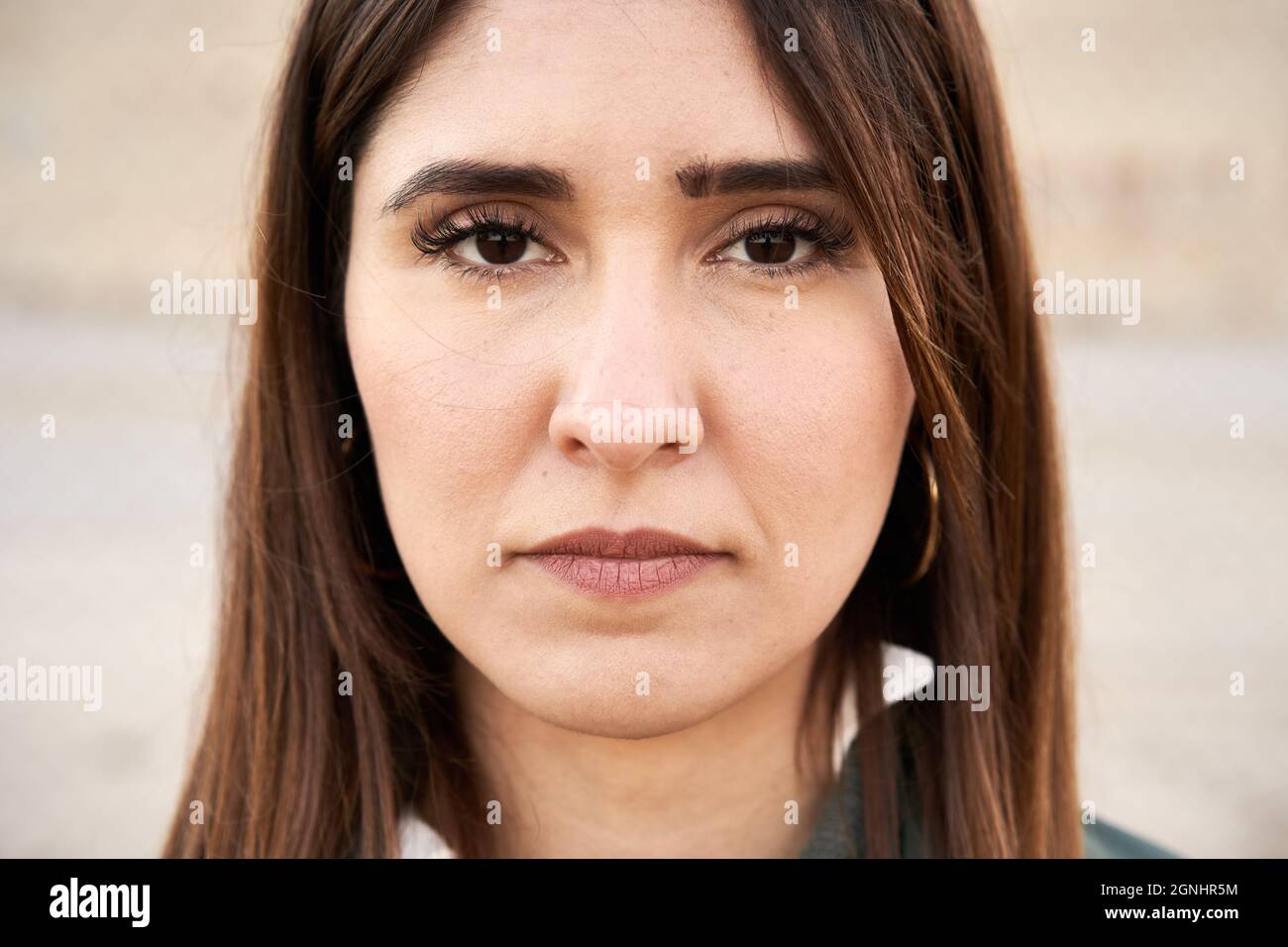 Close-up of a young woman with dark eyes looking at camera with serious ...