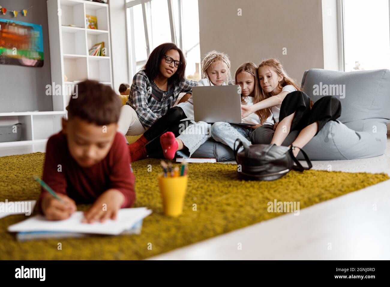 Teacher and girls working with laptop in class Stock Photo - Alamy