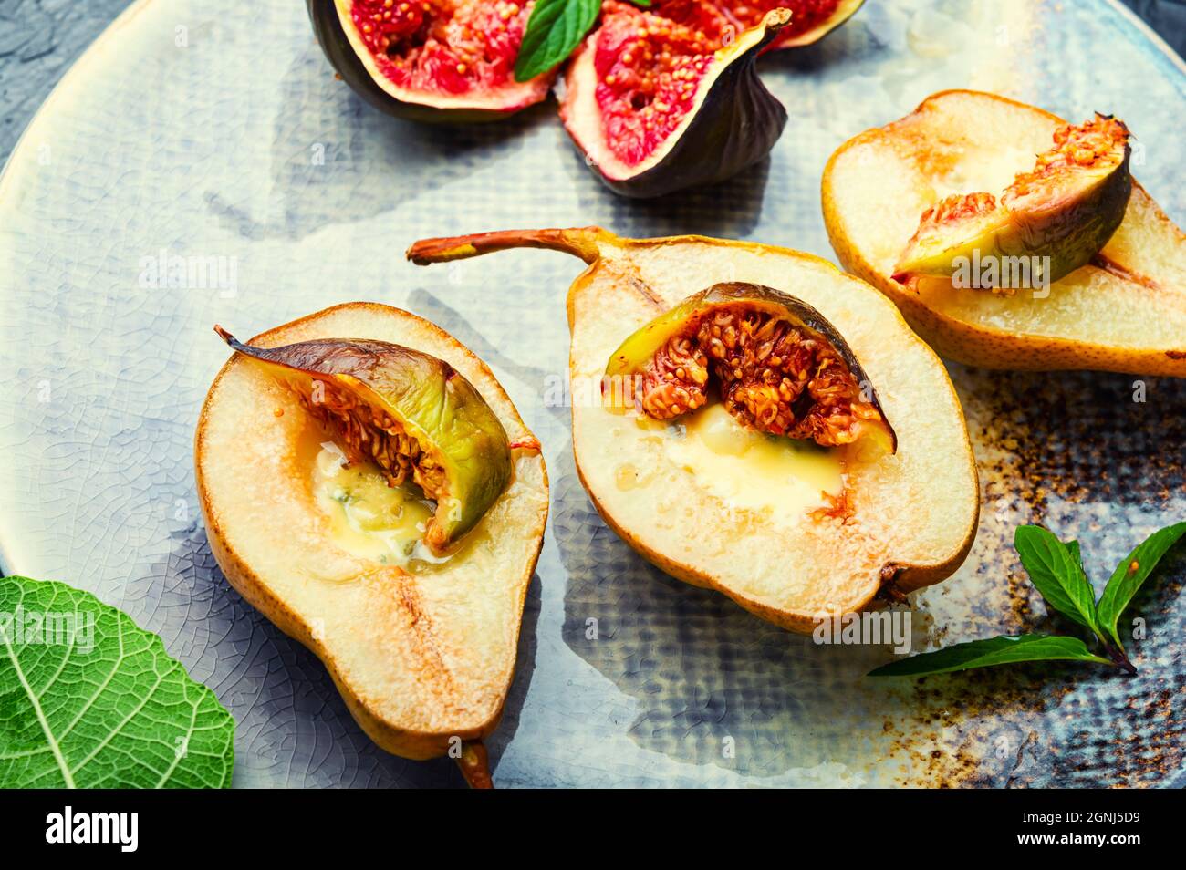 Baked pear halves with figs stuffed with cheese.Autumn snack Stock ...