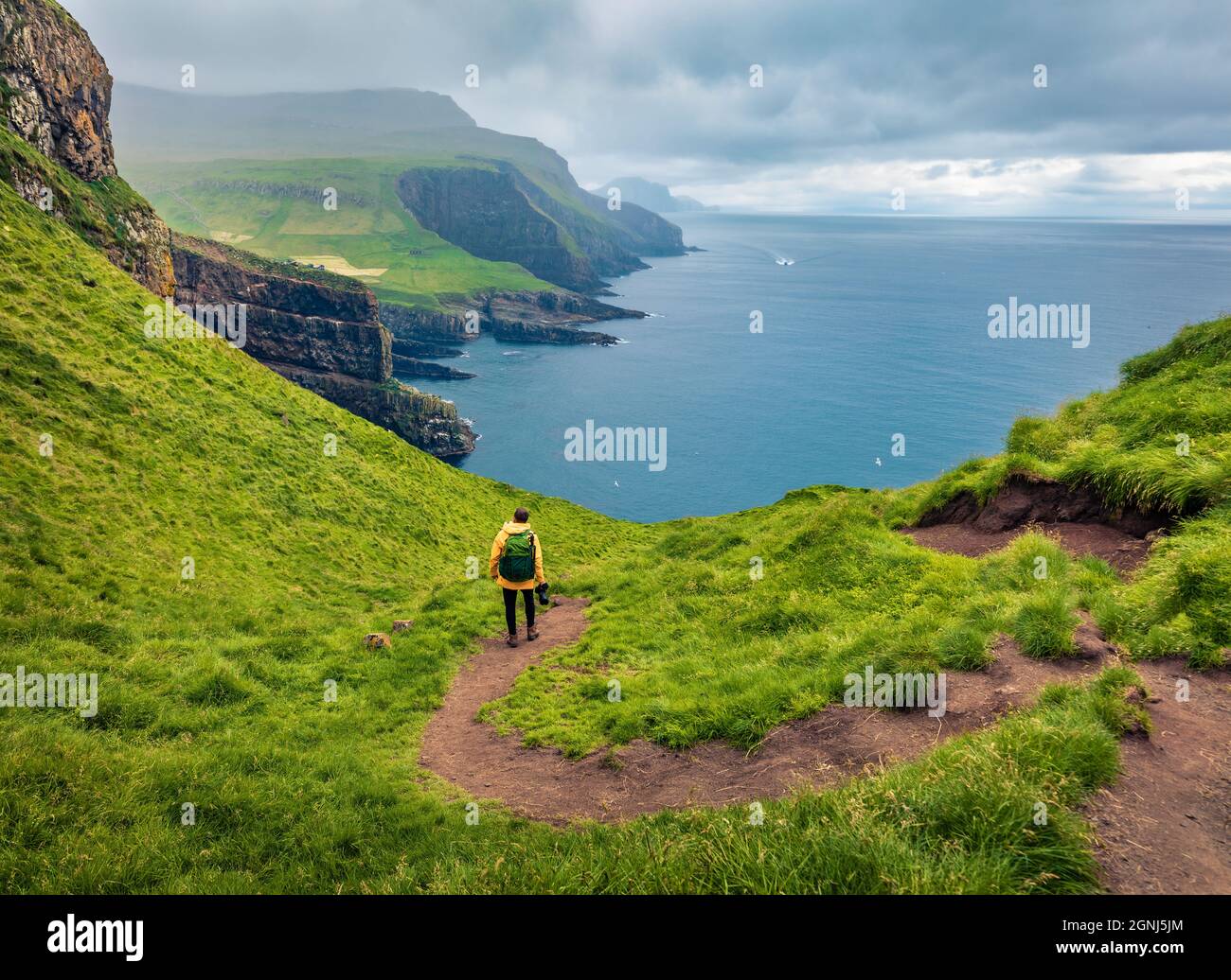 Tourist on trek on Mykines island. Gloomy morning view of Mykines ...