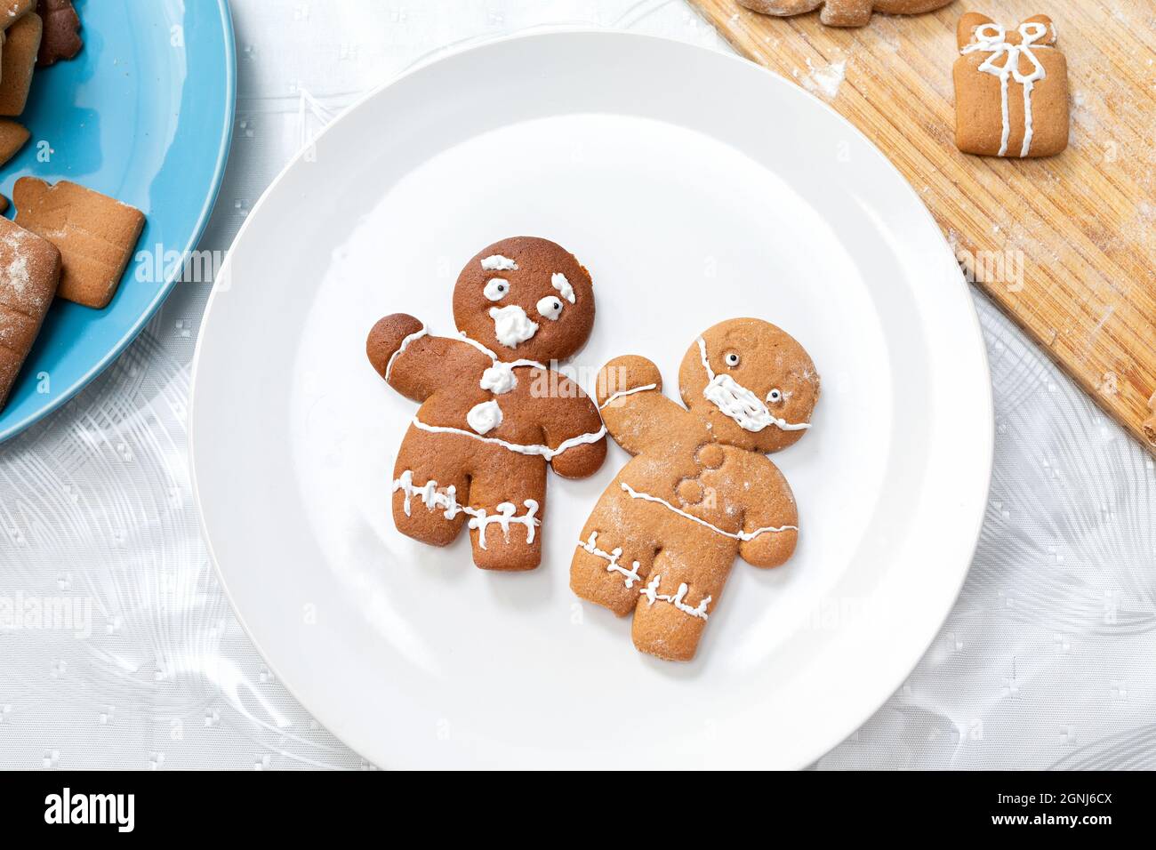 Two gingerbread men, decorated with icing in the form of a medical mask ...