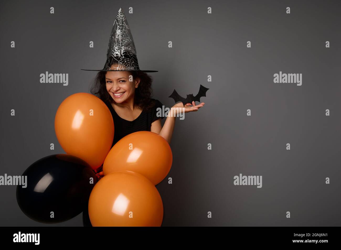 Beautiful mysterious smiling woman in wizard hat, dressed in black ...