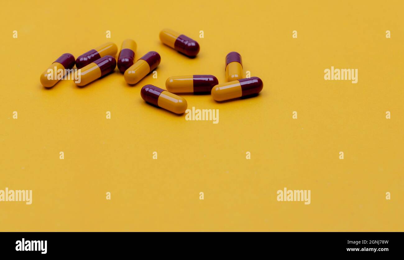 Red-yellow antibiotic capsule pills on yellow background. Prescription ...