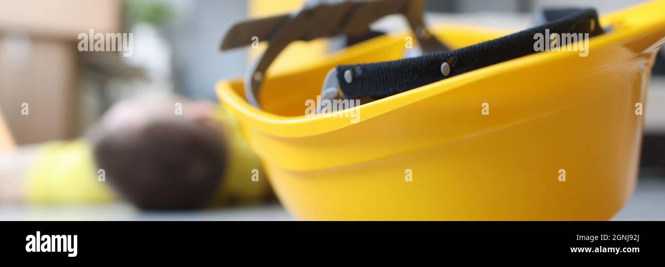 Yellow worker helmet on floor beside motionless construction worker ...