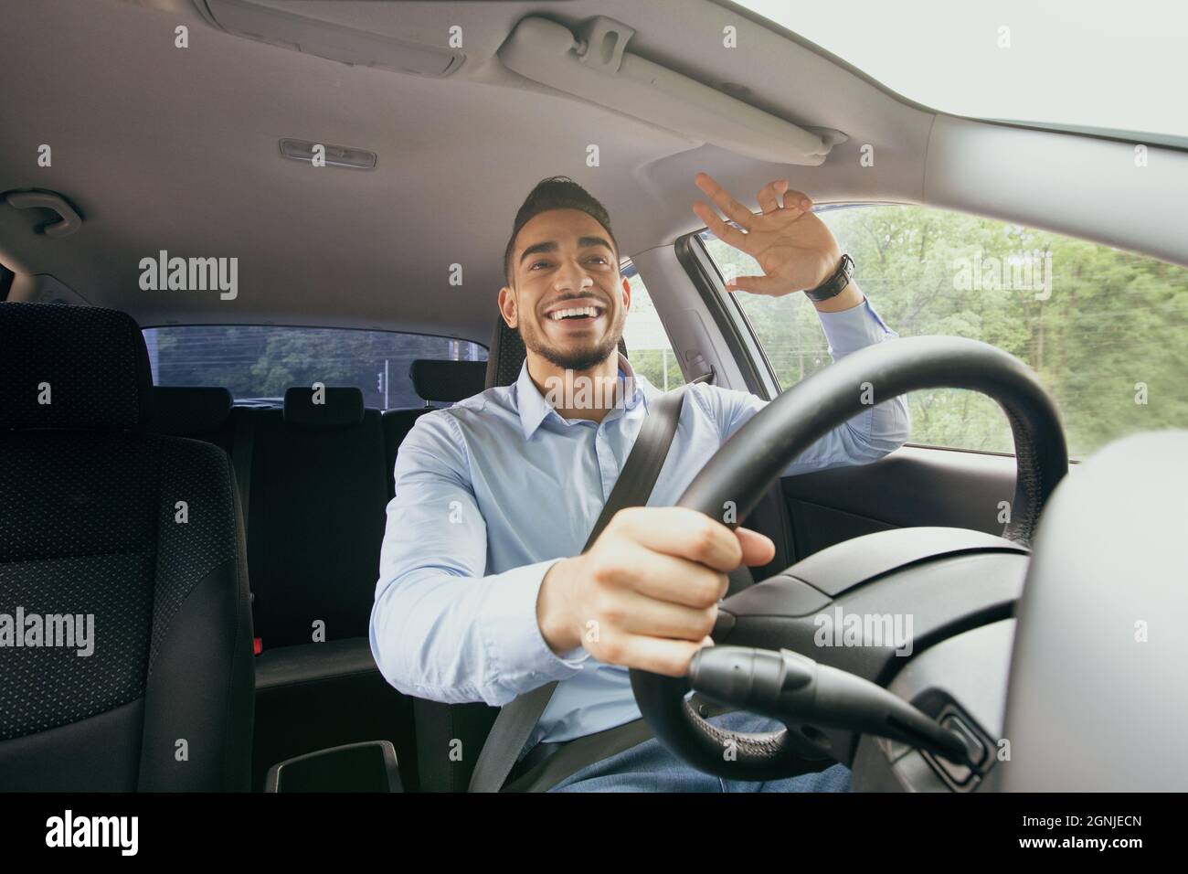 Cheerful middle-eastern guy driving auto, greeting someone Stock Photo ...