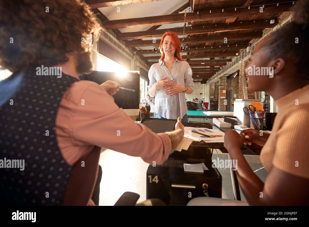 Young colleagues in a pleasant atmosphere at workplace talking about ...