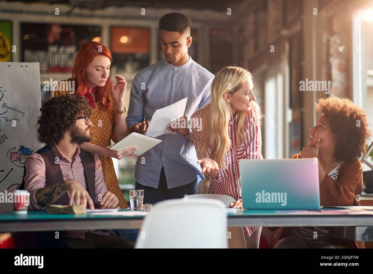 Young creative colleagues brainstorming while working on project in a ...