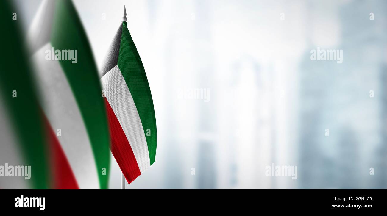 Small flags of Kuwait on a blurry background of the city Stock Photo ...