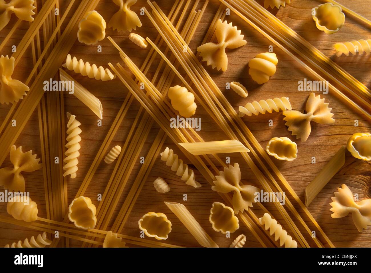 Different type of pasta, on wooden table, with shadows and highlights ...