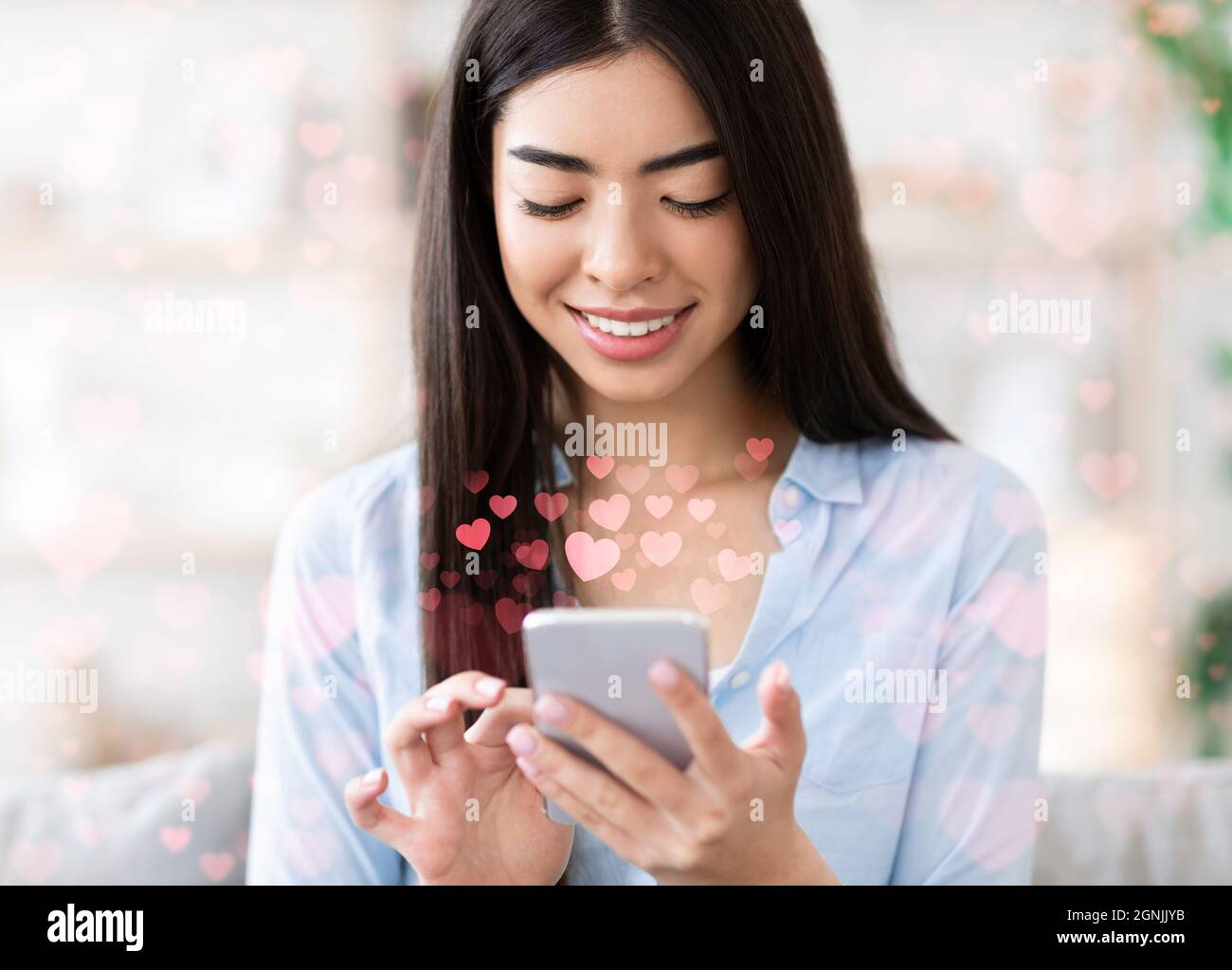 Smiling young asian female has romantic chat with boyfriend on ...