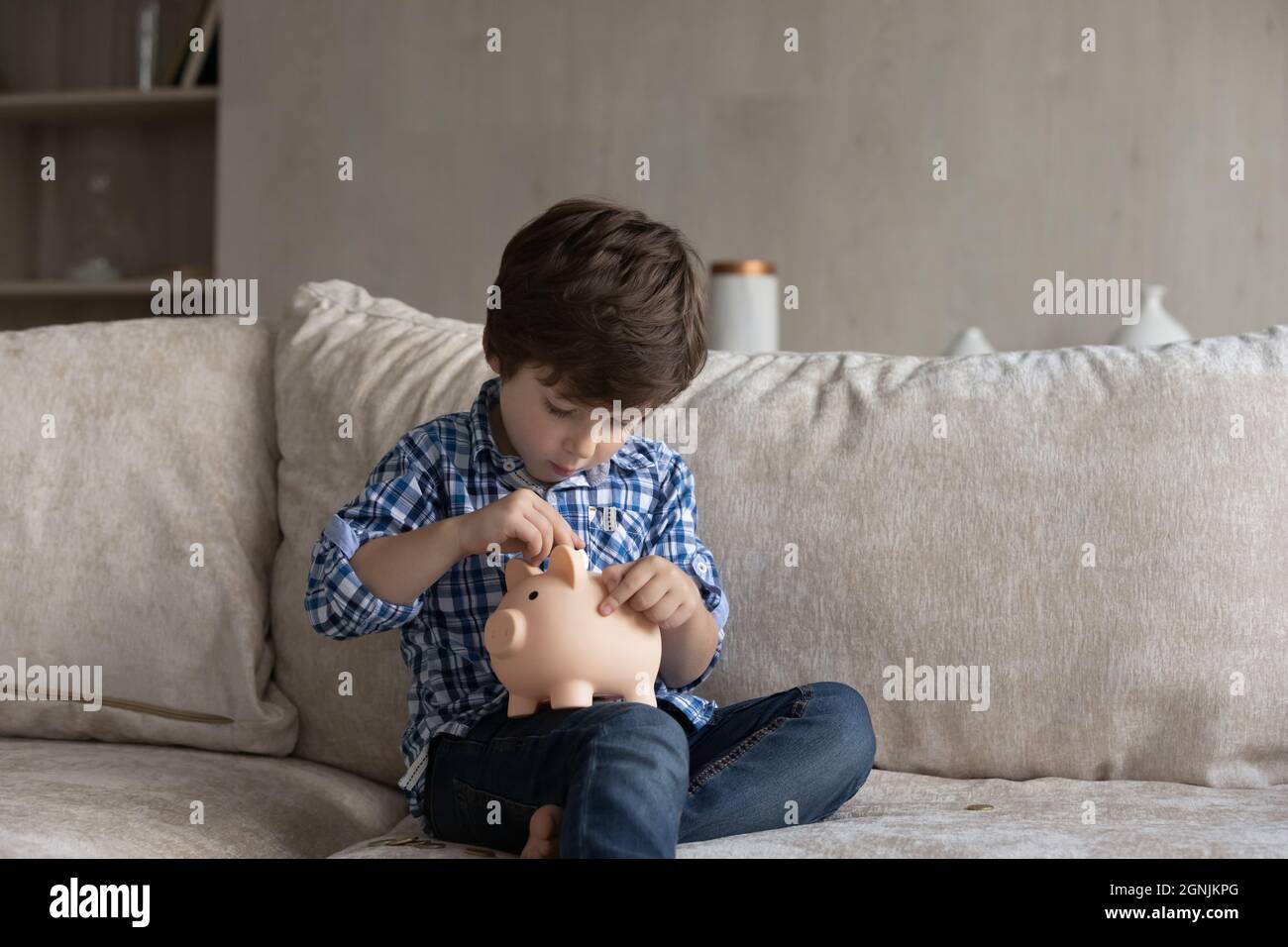Concentrated little cute kid boy saving money for future Stock Photo ...