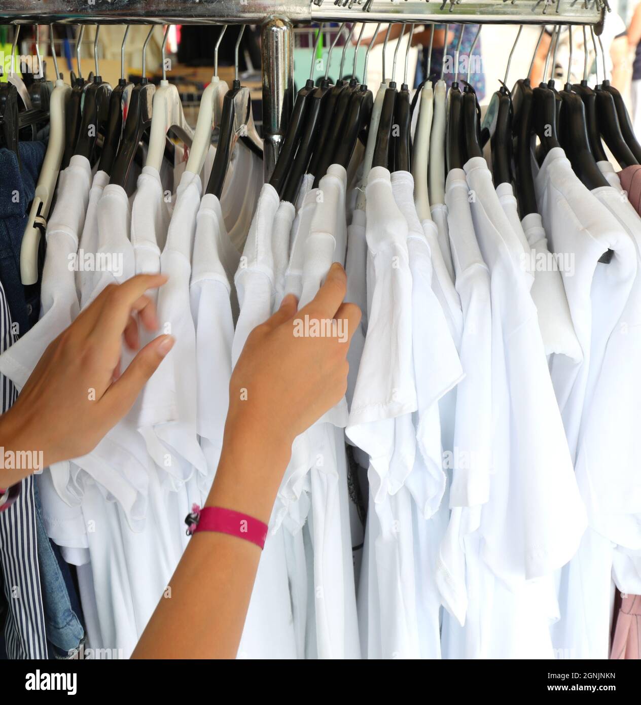 hand of woman who chooses the white blouses hanging from the hangers ...