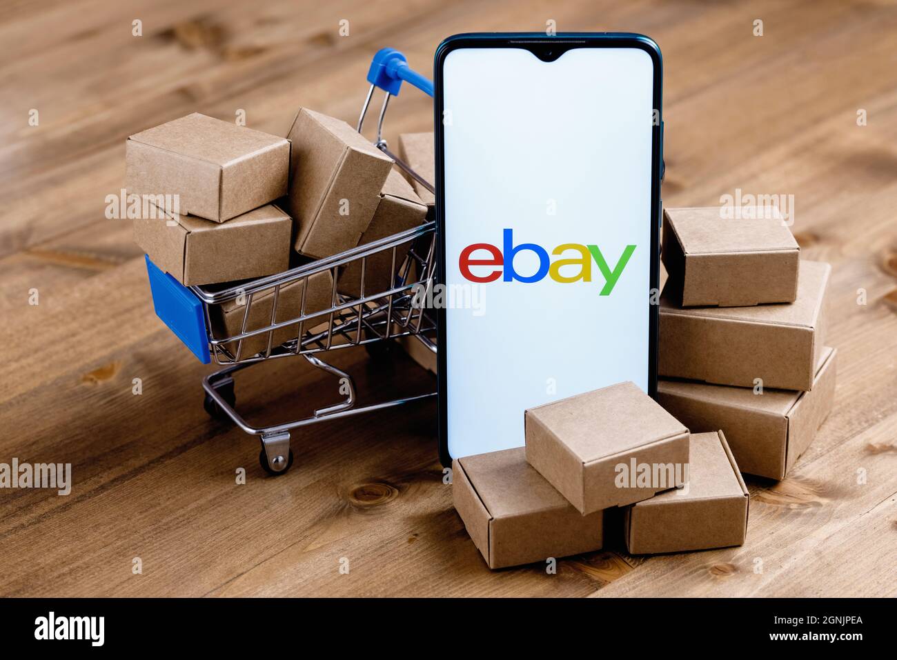 Smartphone with eBay logo on the screen, shopping cart and parcels ...