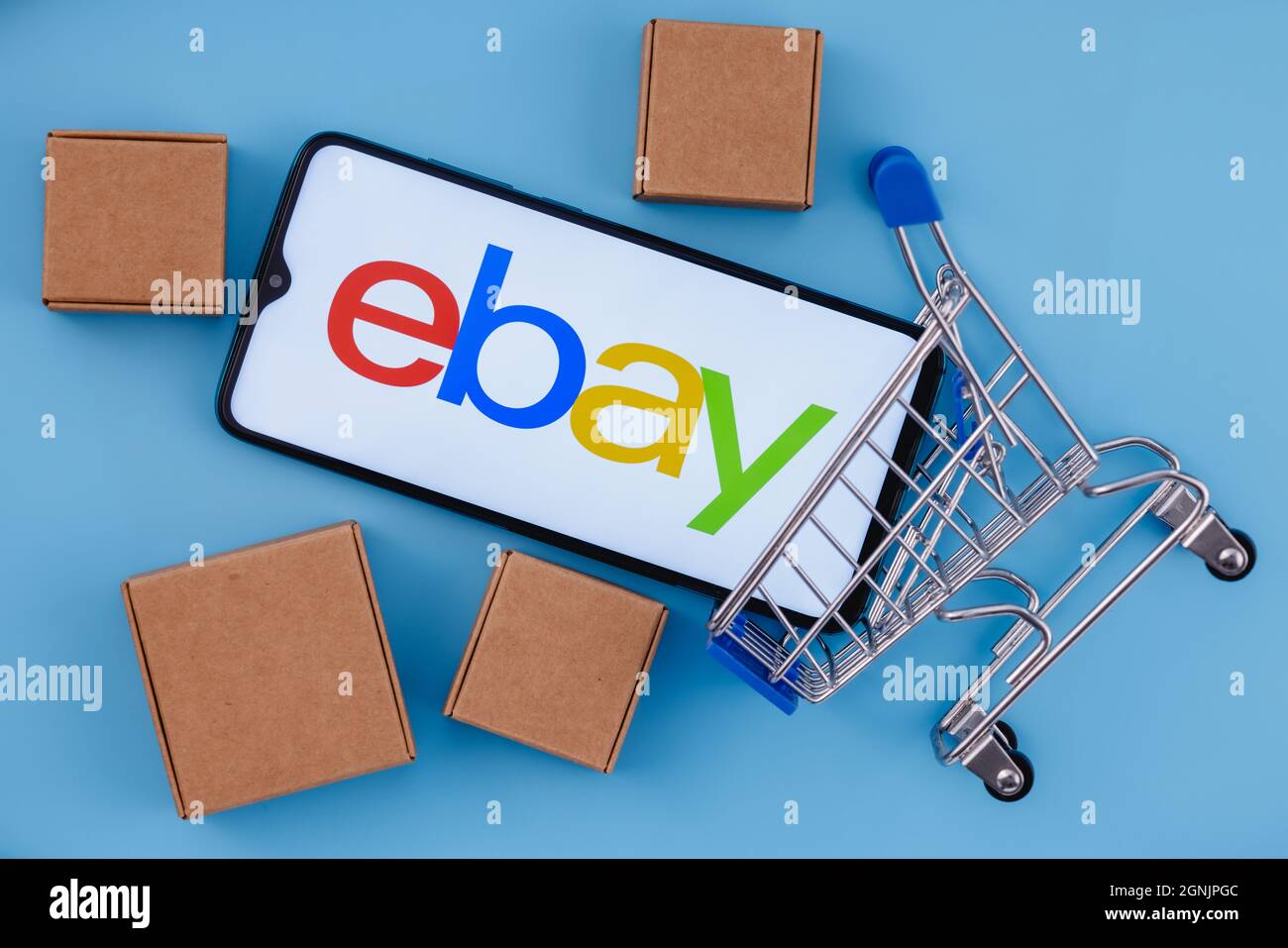 Smartphone with eBay logo on the screen, shopping cart and parcels ...