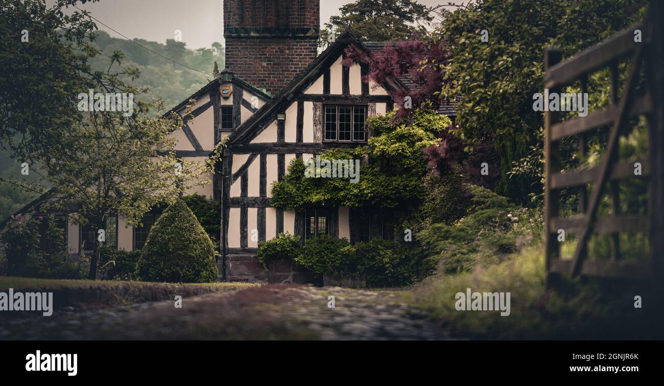 Old fashioned Tudor vintage home along a gravel driveway behind a gate ...