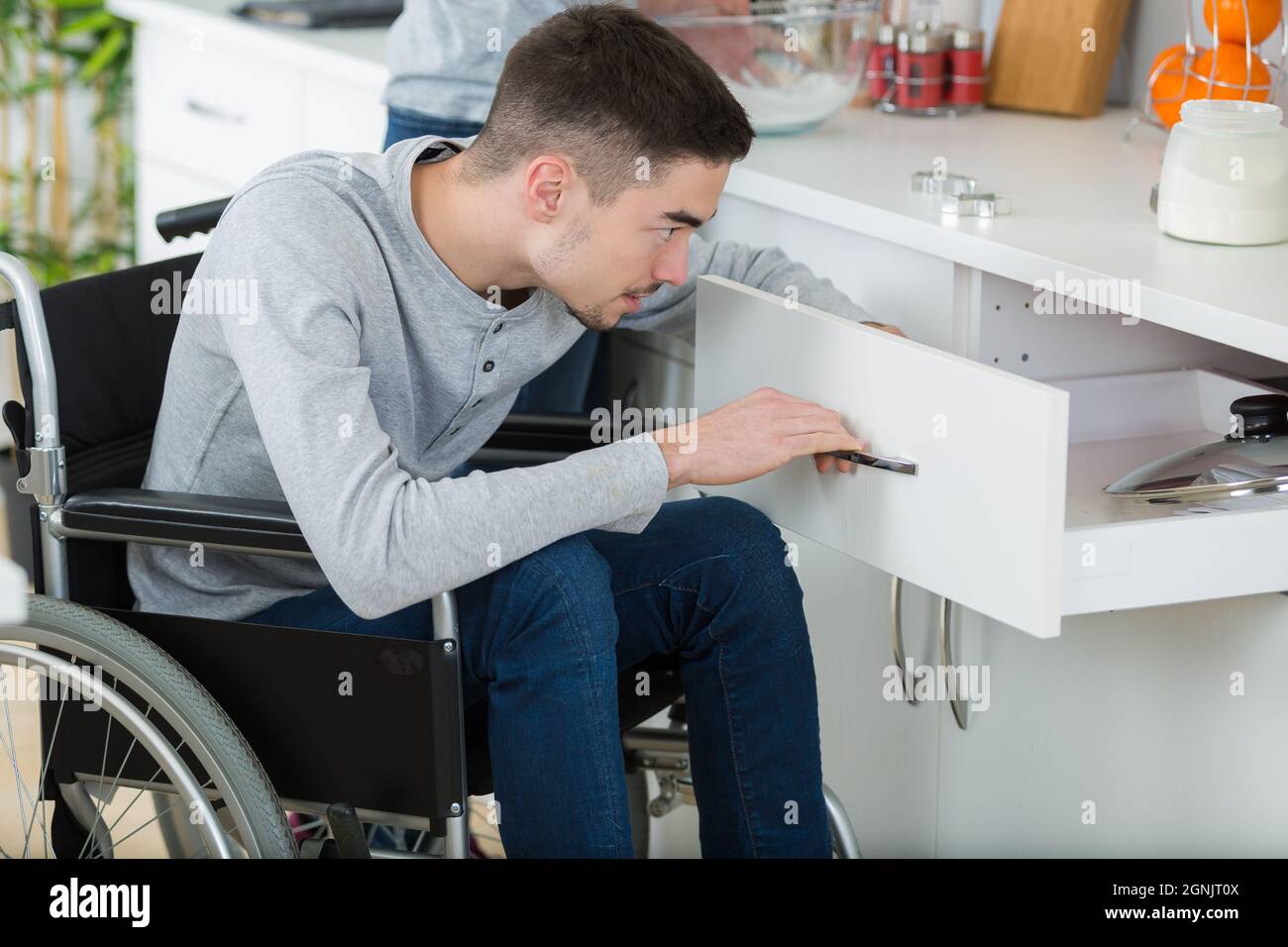 young man on the wheelchair opening the drawer Stock Photo - Alamy