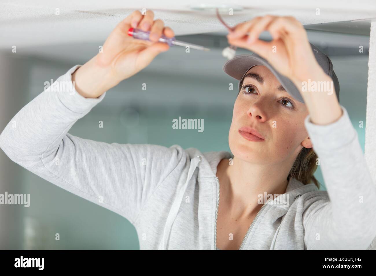 woman on ladder fitting light bulb in new house Stock Photo - Alamy
