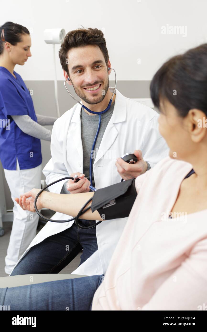 doctor performing blood pressure check on female patient Stock Photo ...
