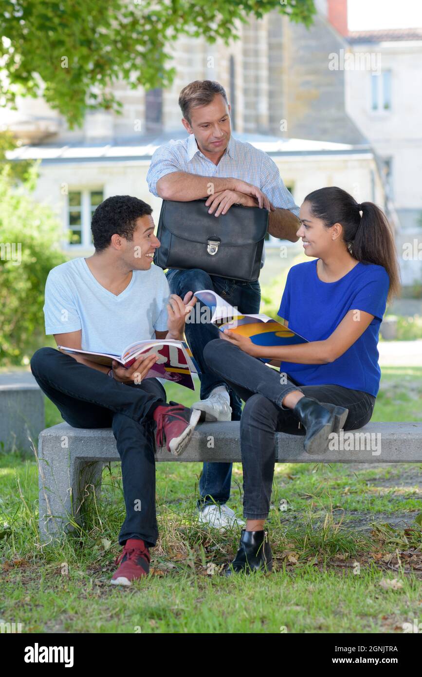 professor talking to students relaxing on the bench Stock Photo - Alamy